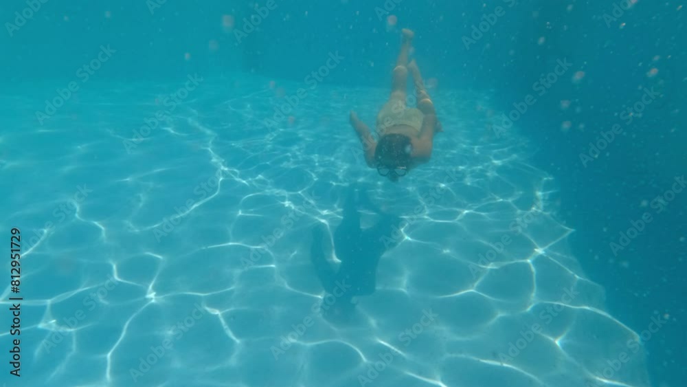Underwater view of a teenage boy swimming in a clear blue pool, wearing ...
