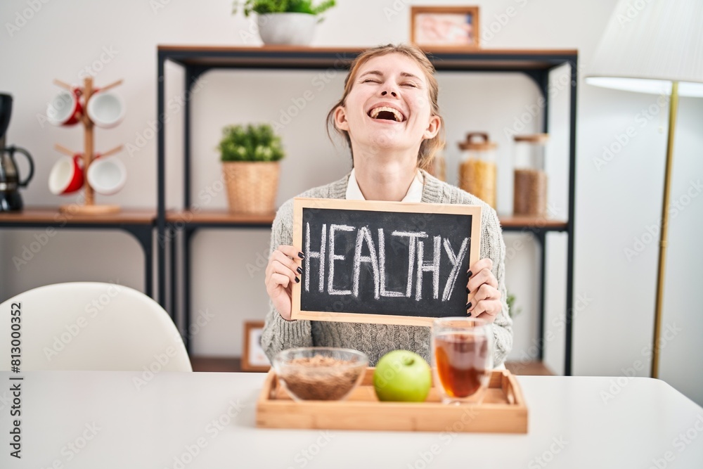 Belly-laughing young blonde beauty enjoying a healthy breakfast at home ...