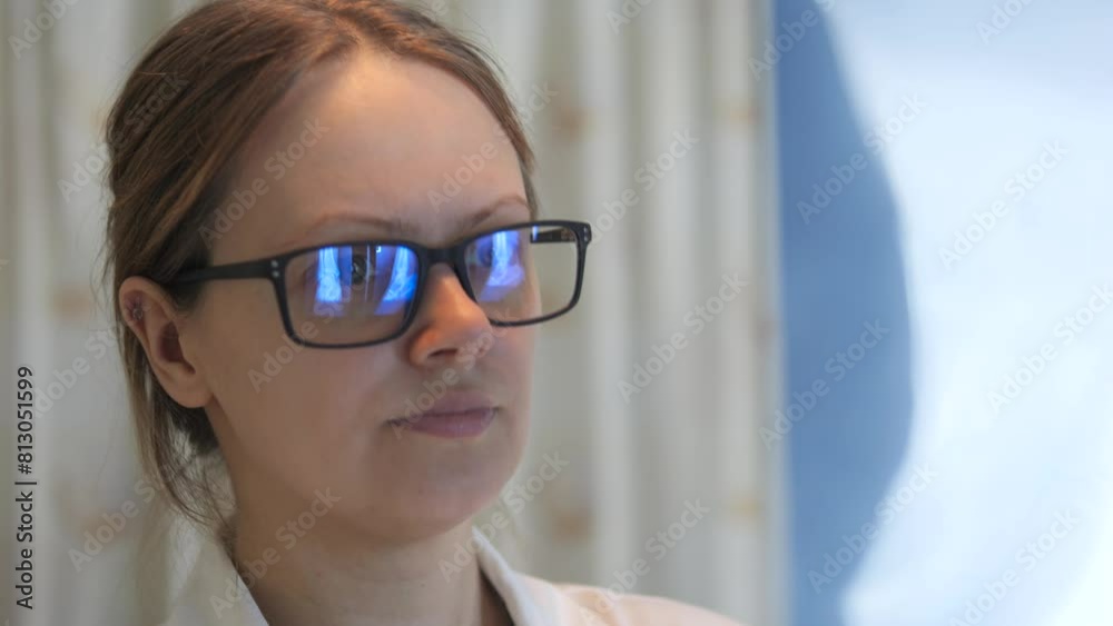 Female doctor reading X-ray scans MRI images. Reflection in glasses ...