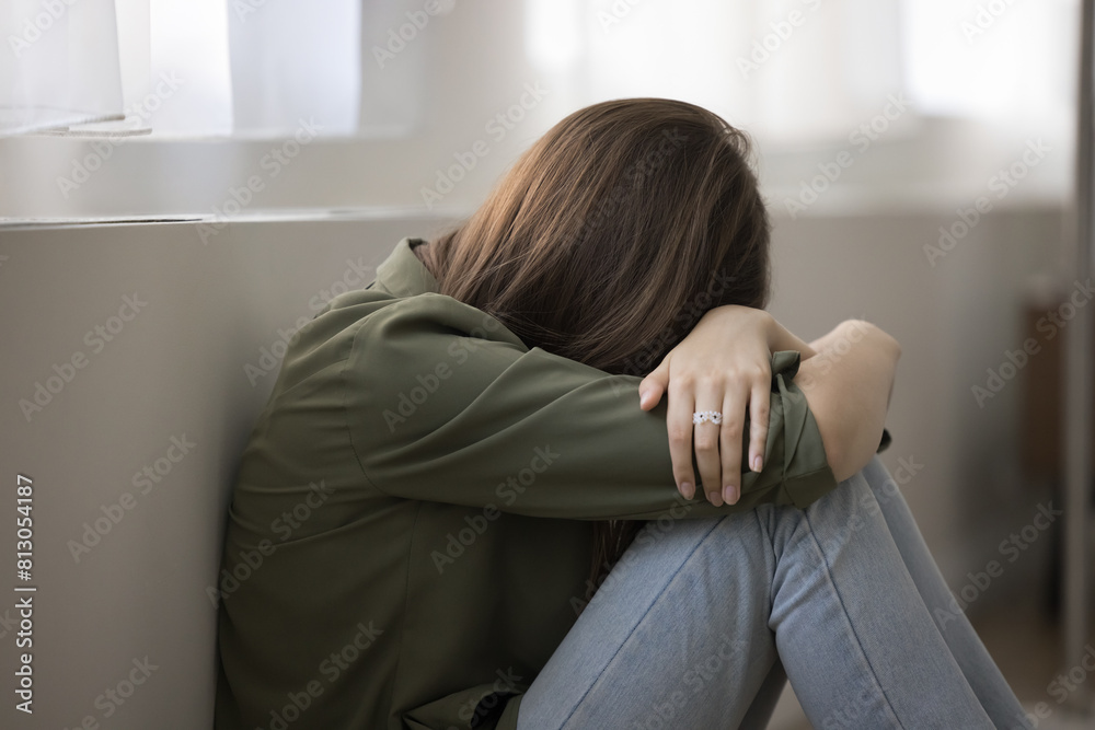 Sad depressed teenager girl sitting on floor indoors, hiding face ...