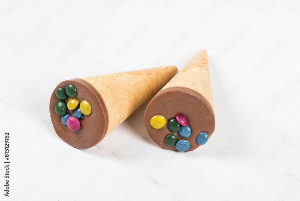 Two waffle cornets, with chocolate nut cream and colored dragees. White ...