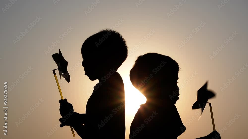 Two boys stand under the hot sun and play with two pinwheel fans ...