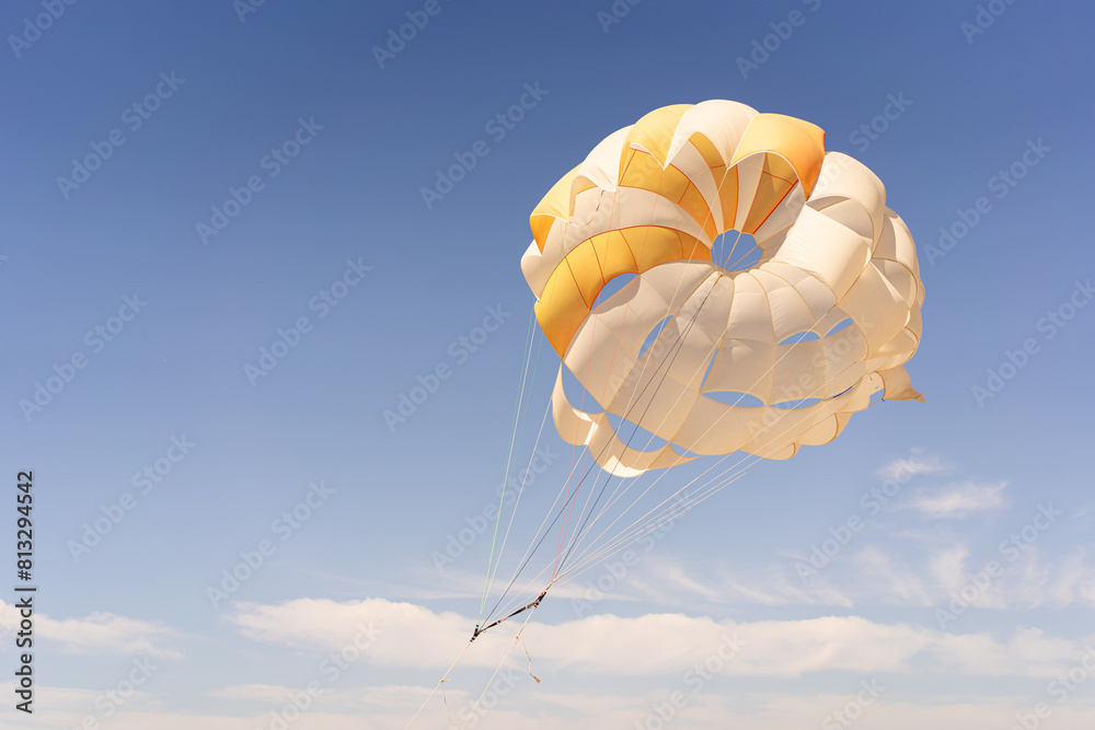 The parachute is fully inflated, showcasing vivid yellow and white ...