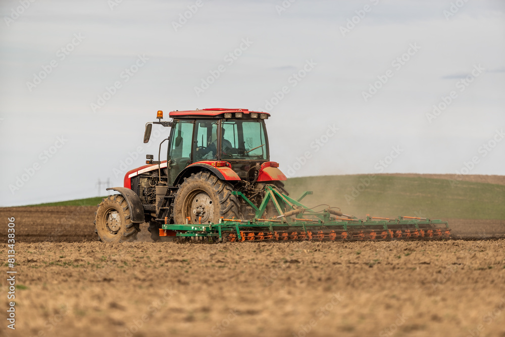 A modern tractor tilling farmland, preparing the soil for planting ...