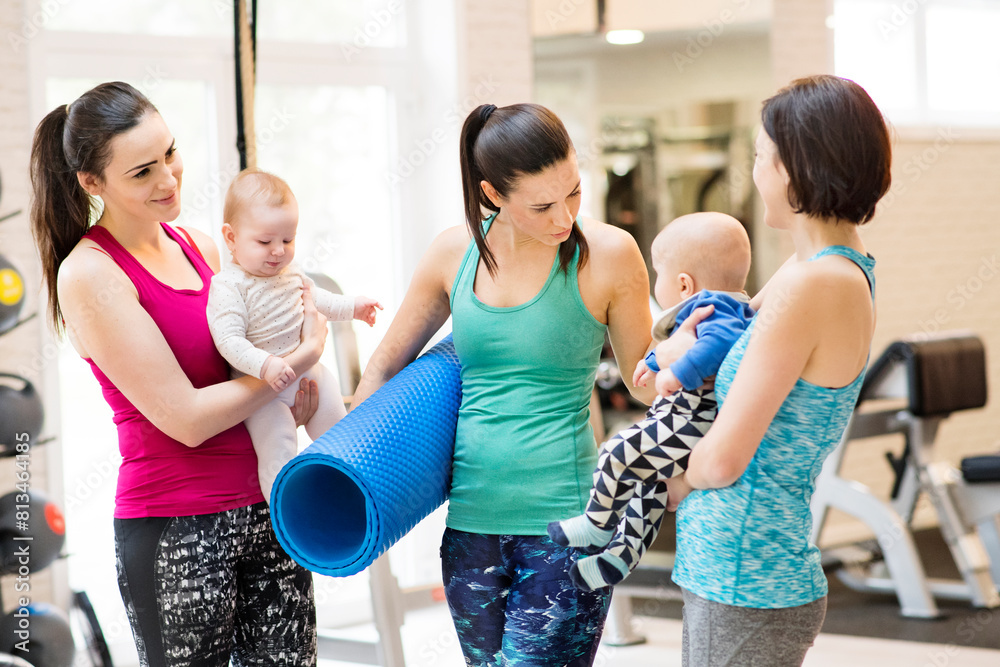 Group exercise class, mother working out with baby in gym. Moms staying ...