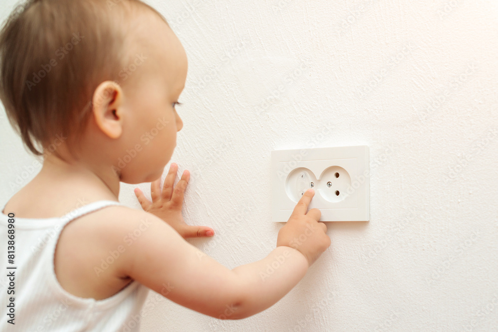 Baby touching the power socket. Baby and child safety concept. Curious ...