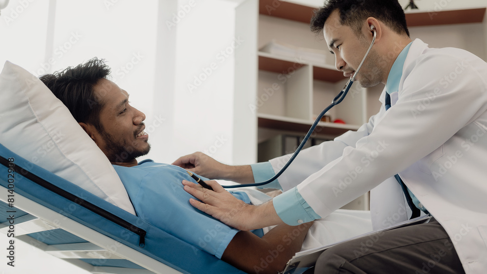 A young man lies on a bed in a hospital ward talking with her young ...