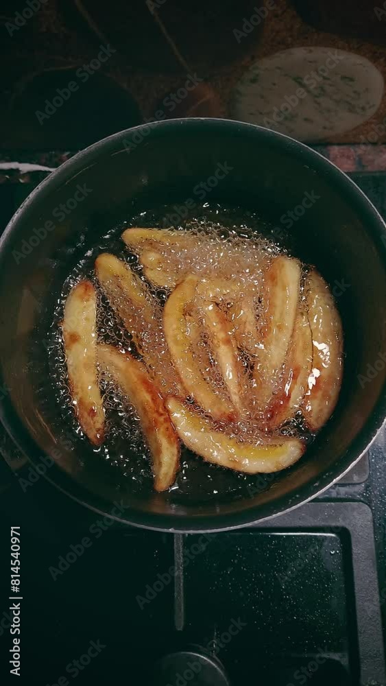 Vertical overhead view of a pot with banana slices being deep-fried ...