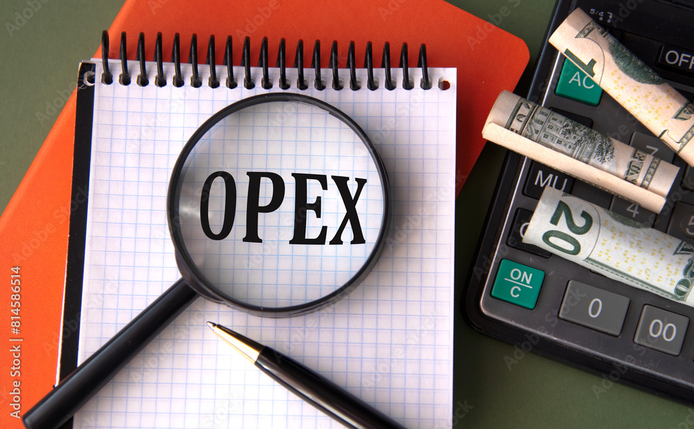 OPEX - word under magnifying glass on the background of calculator and ...
