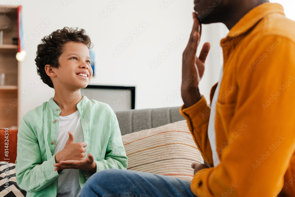 Smiling, positive African American little boy and his dad communicating ...