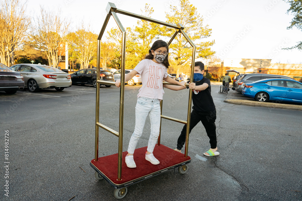 Boy pushing a girl on a luggage cart. Stock Photo | Adobe Stock