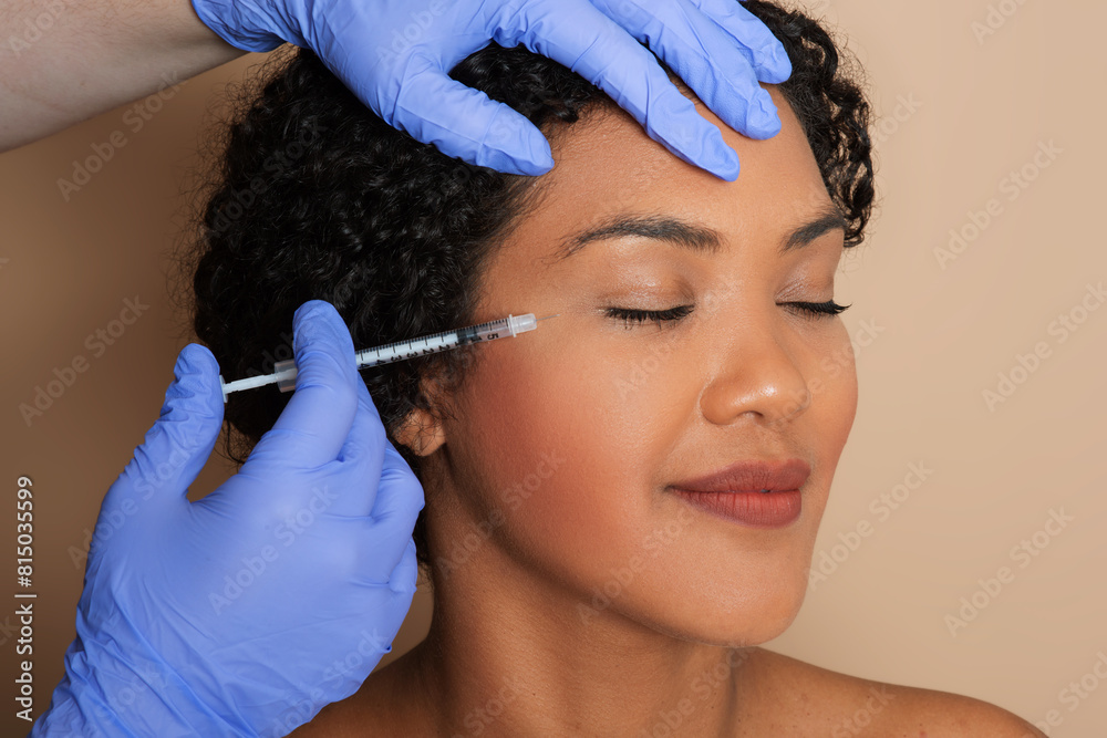 A woman is undergoing filler injection treatment on her facial skin ...