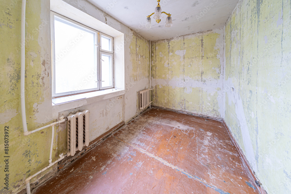 Renovation in a small bedroom with bare walls with peeled wallpaper ...