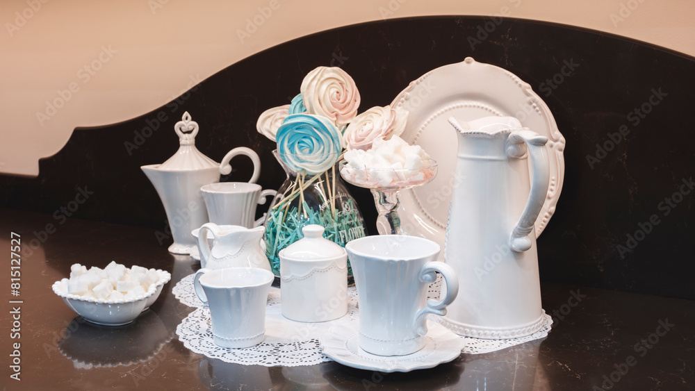 A white tea set is displayed on a counter with a lace doily. The tea ...