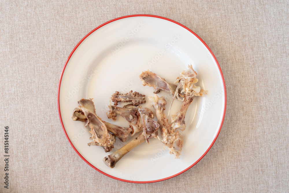 Plate with chicken bones on cotton fabric background. Leftover food ...