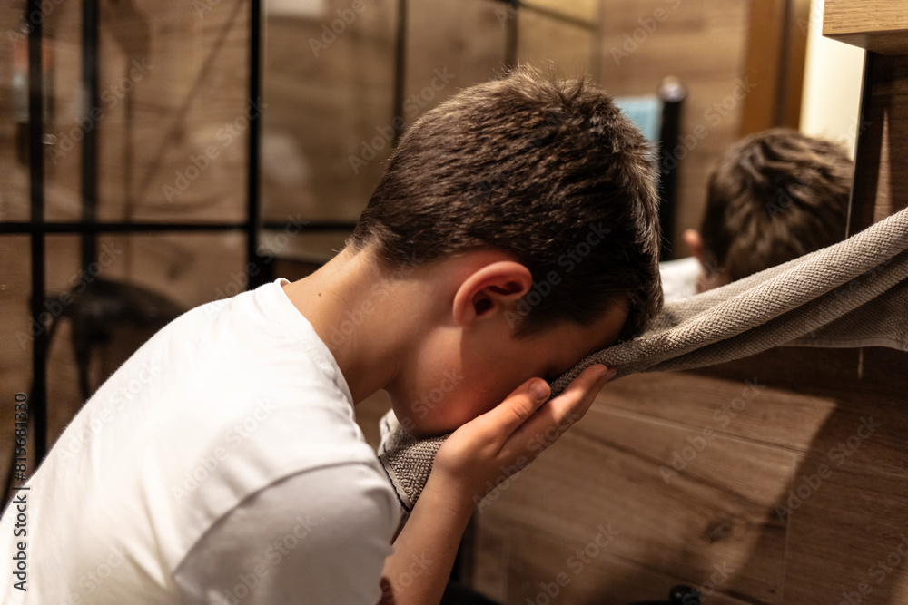 Boy drying his face with a towel in the toilet. Morning boy wiping his ...