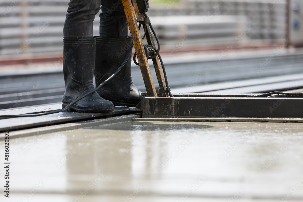 Construction worker operating machine spreading wet concrete pouring at ...