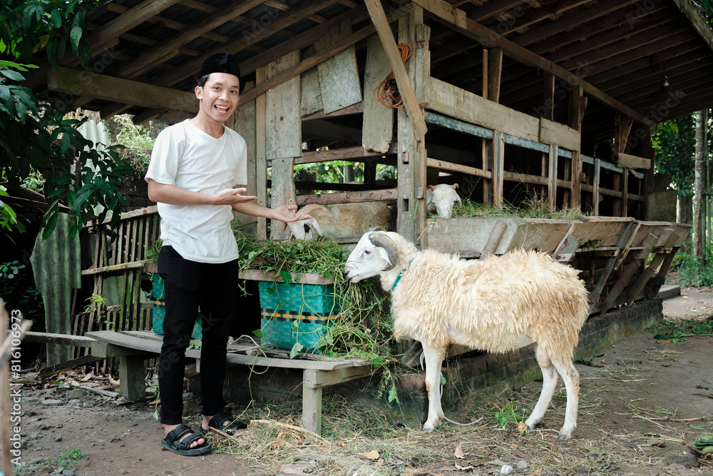 Muslim man standing showing his goat at goat farm. eid al adha concept ...