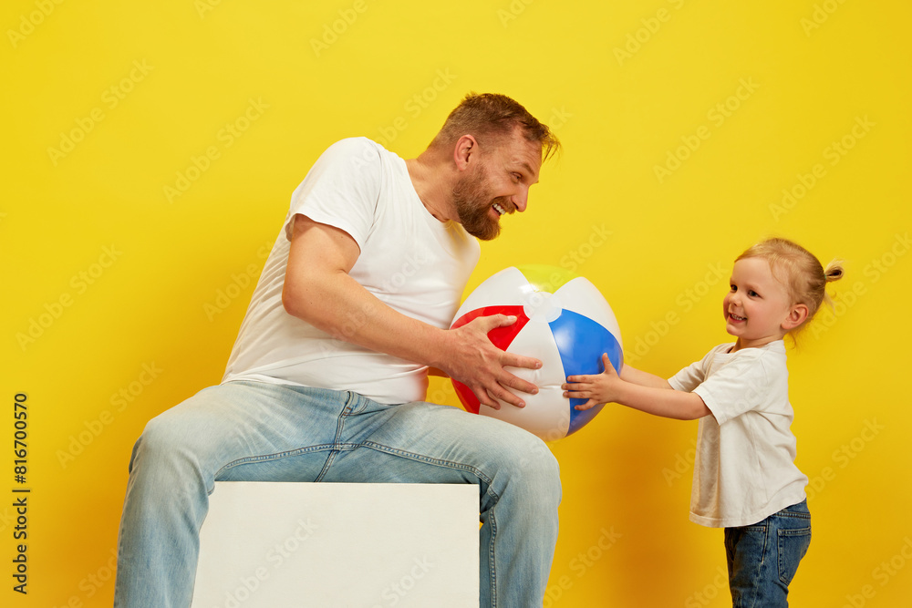 Happy dad and his excited son playing catch with colorful beach ball ...