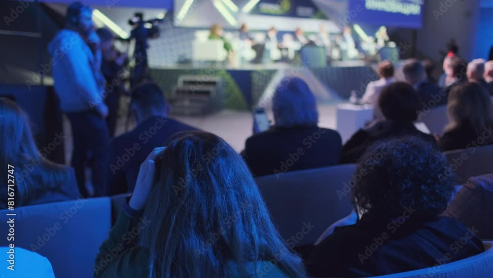 Vidéo Stock Back view of an audience listening intently to a panel of ...
