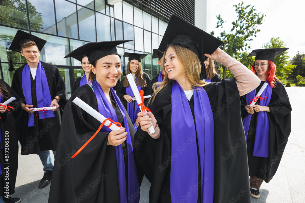 Group of happy graduates standing in front of school with togas and ...