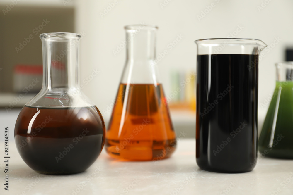 Flasks and beaker with different types of crude oil on light table ...