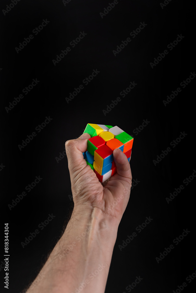 Rubiks cube in a persons hands, portrait, black background. Man holding ...