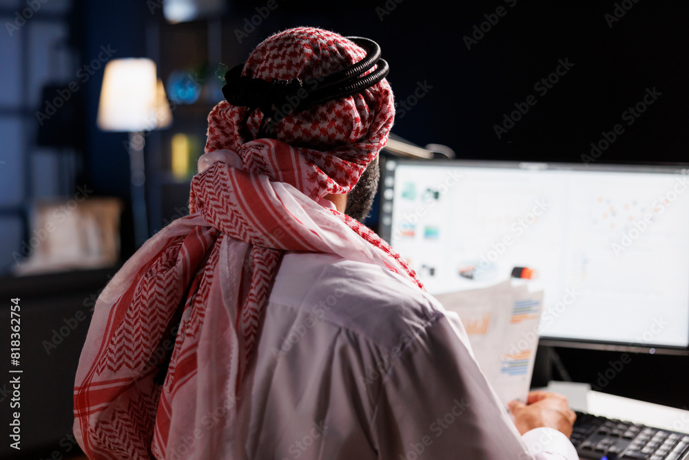 Focused Arab businessman diligently works at his desk, conducting ...