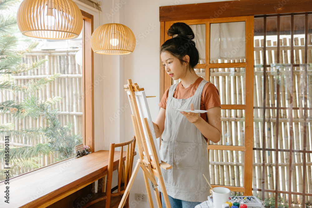 Asian young talented woman artist coloring on painting board in house ...