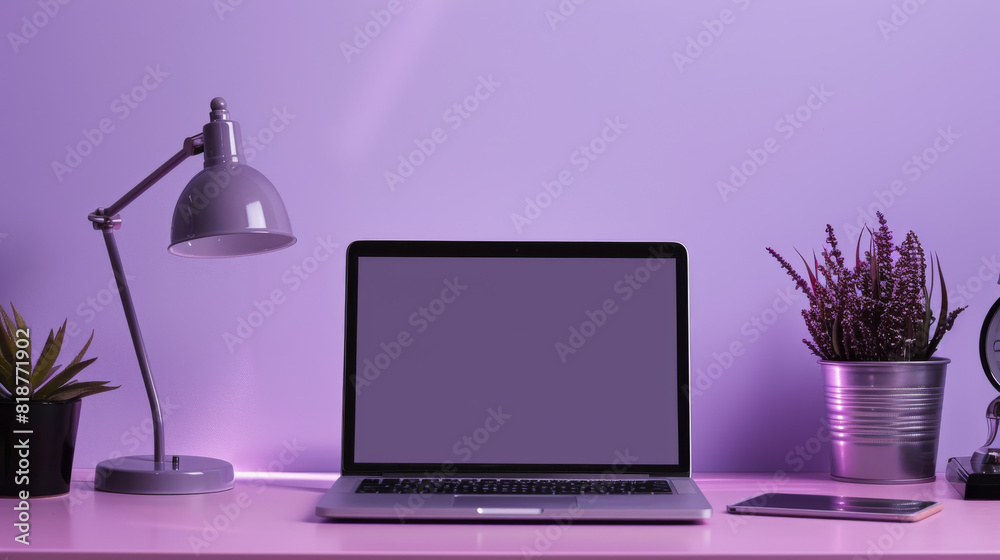A laptop sits on a desk with a purple background. The laptop is open ...