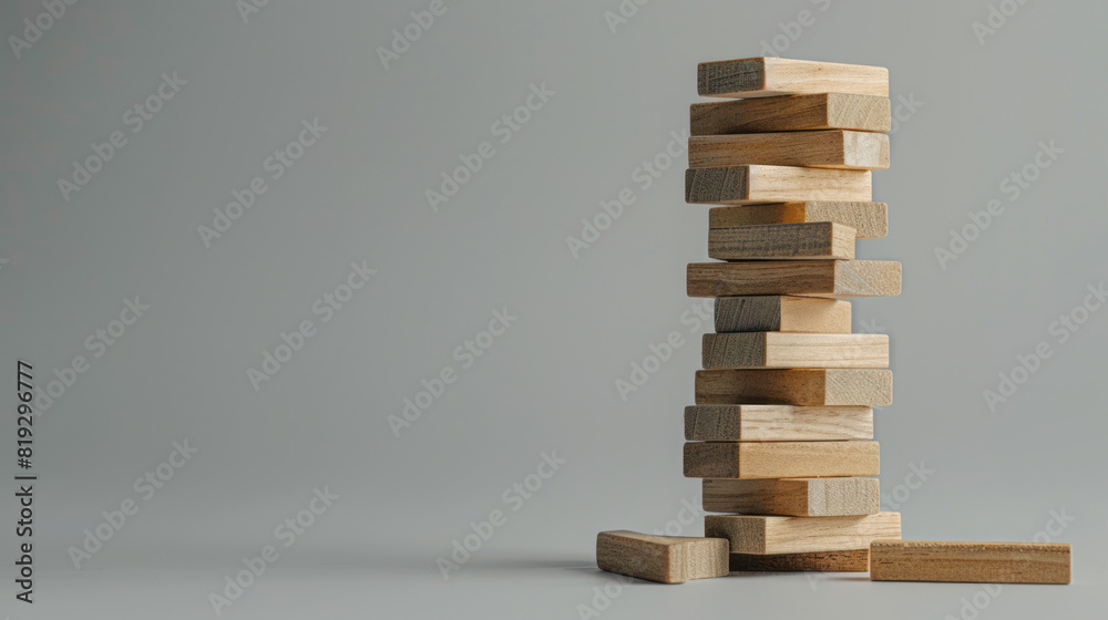 Stack of wooden blocks forming a tall Jenga tower on a gray backdrop ...