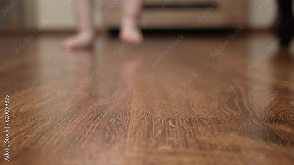 The baby's bare feet stomp on the parquet floor. Close-up. Blurred ...
