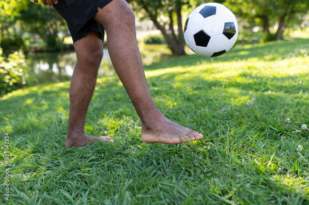 Young black football player playing with a soccer ball barefoot on the ...