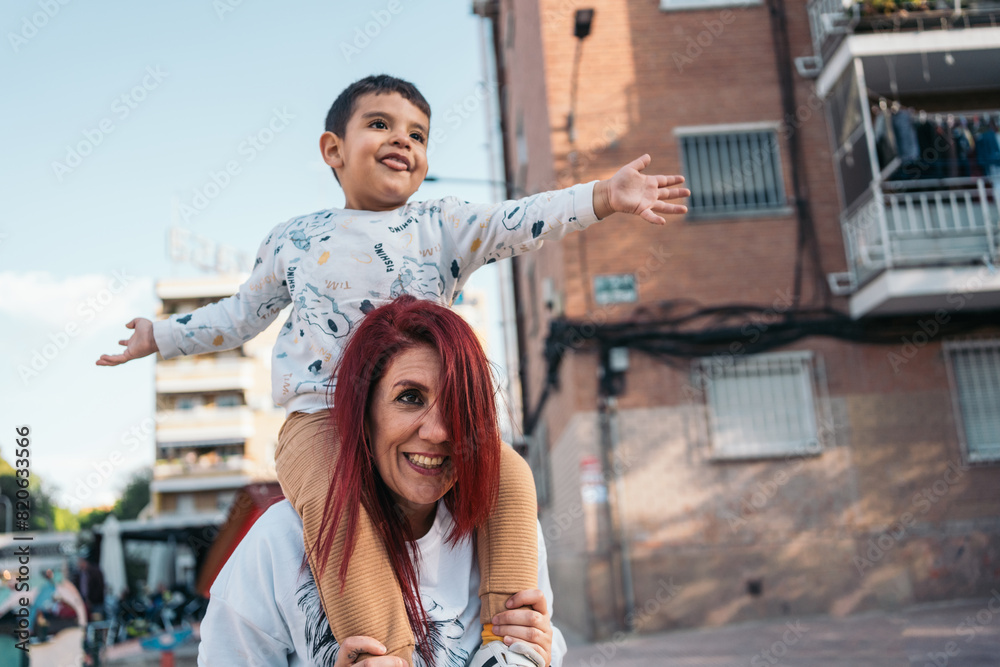 Joyful autistic child riding shoulders of smiling woman outdoors. Happy ...