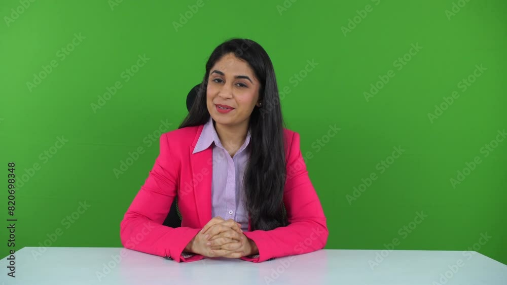 A young Indian news anchor delivering a speech on the green screen ...