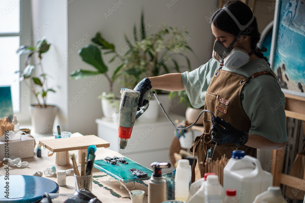 Artist girl works with flowable epoxy resin creates paintings in studio ...