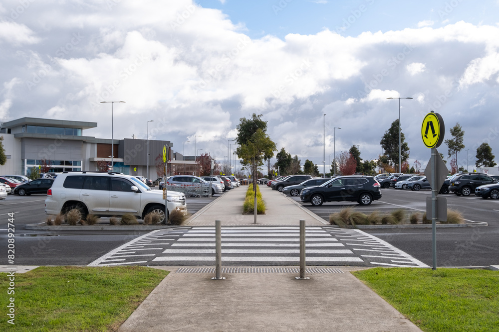 A crosswalk leads to a footpath in an outdoor parking lot outside a ...