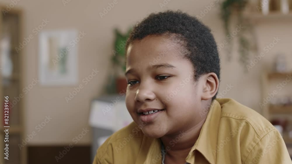 Medium tilting of focused 10-year-old African American boy sitting on ...