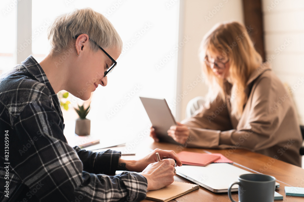 Two busy young female students e-learning studying working remotely ...