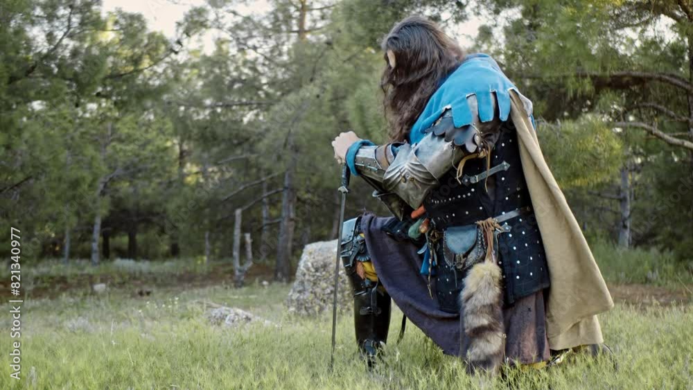 A man in a medieval knight costume stands kneeling and leaning on a ...