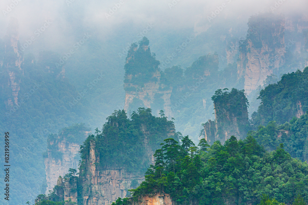 Irregularly shaped sandstone cliffs partly shrouded in fog, Zhangjiajie ...