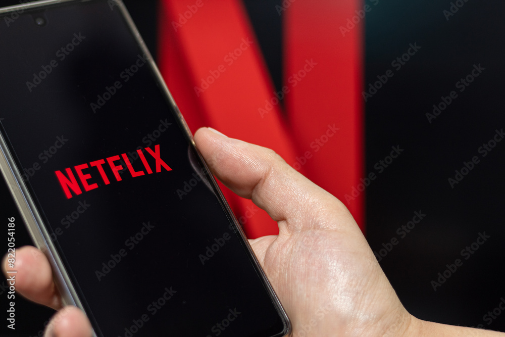 Hand holding a cell phone with the Netflix app on the screen. Netflix ...