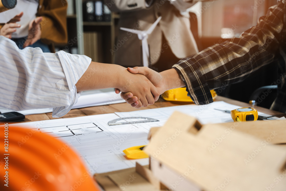 Construction workers, architects and engineers shake hands while ...