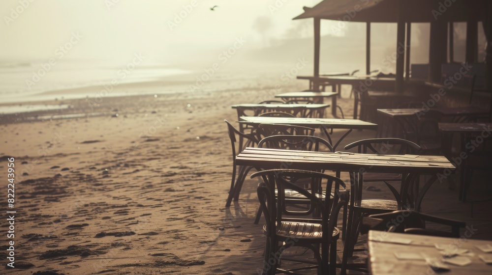 An atmospheric scene of a beachside cafe with empty chairs and tables ...