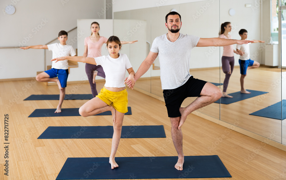 Friendly sporty family of four practicing partner yoga in fitness ...