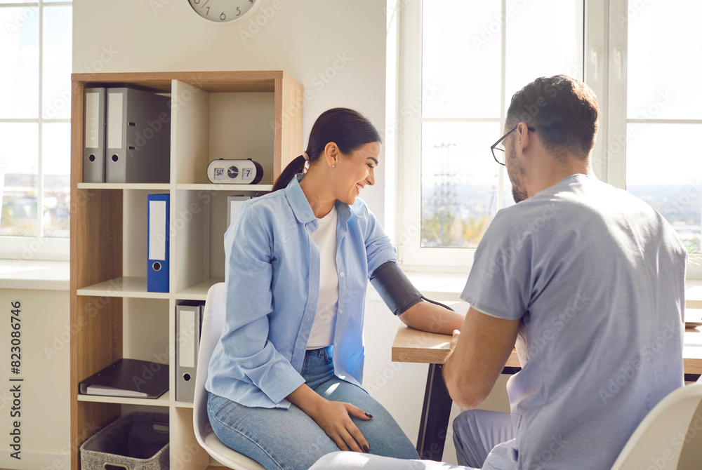 Doctor with blood measure monitor and female patient, physician office visit for consultation ...