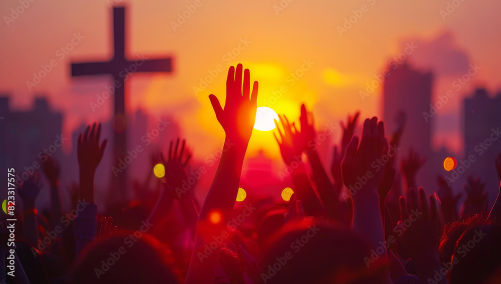 People raising hands in worship at sunset with city silhouette and ...