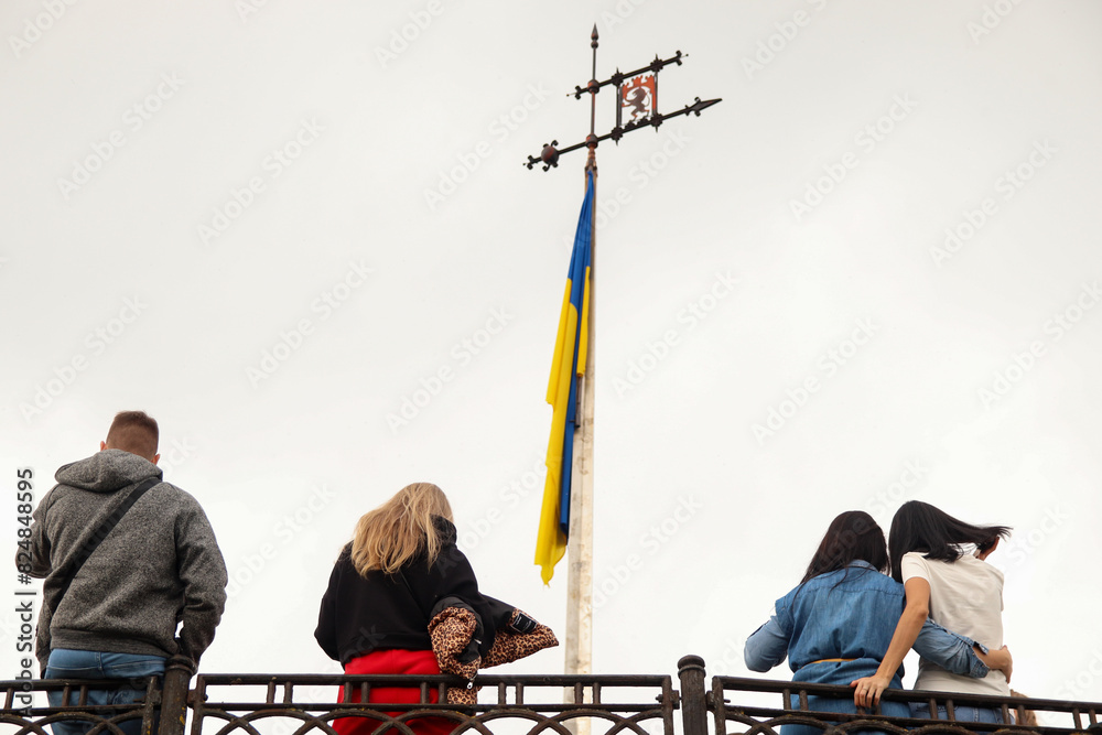 Ukraine people. Back view. Ukrainian flag background on the grey sky ...