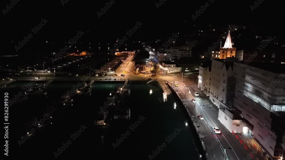 Flight at night along illuminated St Peter Port seafront in Guernsey ...