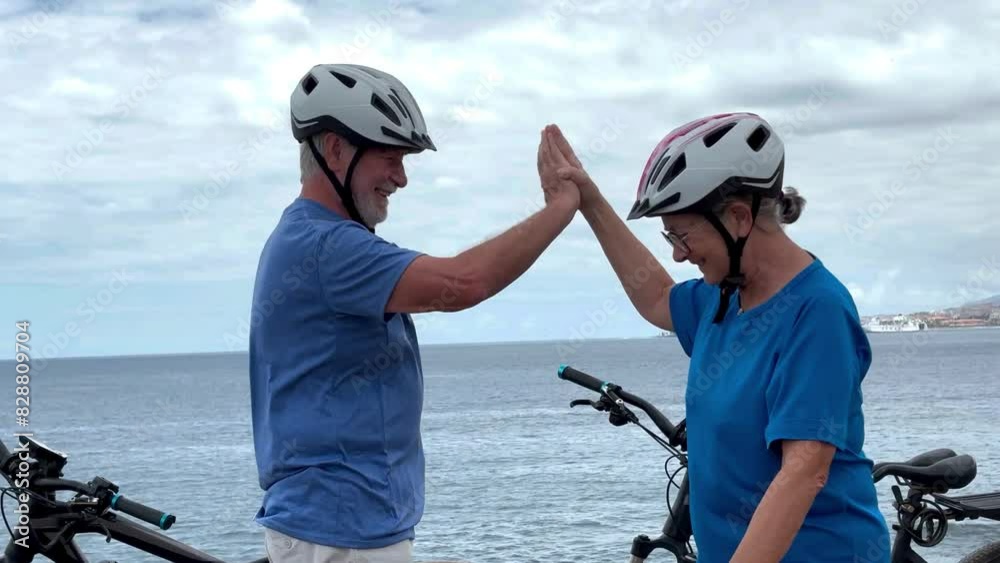 Carefree sporty couple of seniors in activity biking with electric ...